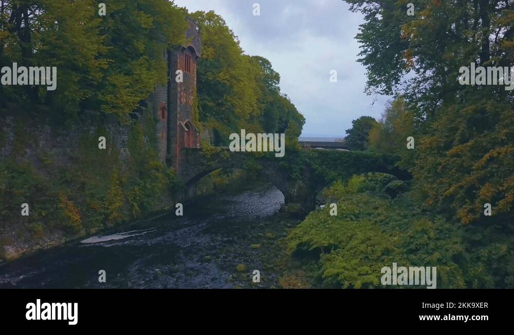 A medieval bridge crossing to a gated castle entrance over a secluded ...