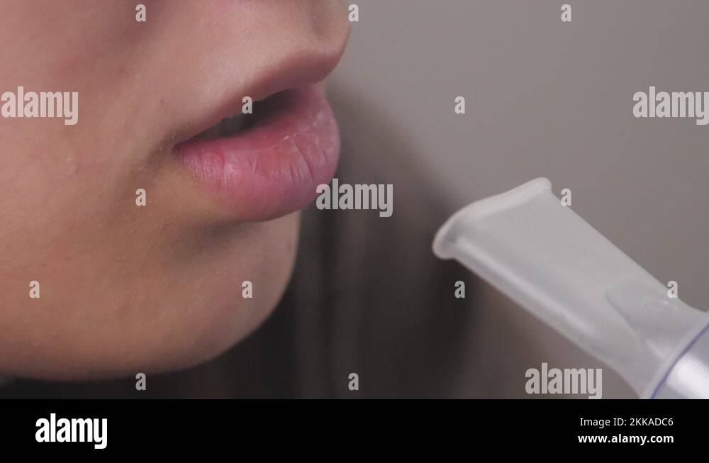 Woman in glasses is using the inhaler and taking deep breaths. Portrait ...