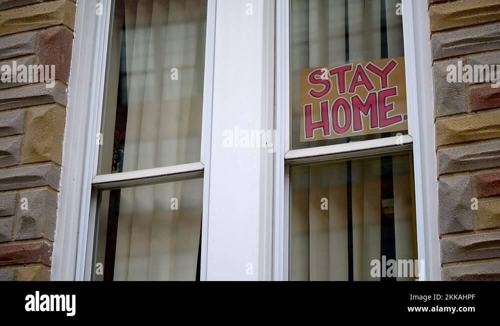 A handwritten sign reads "Stay home" in a residential window with close ...