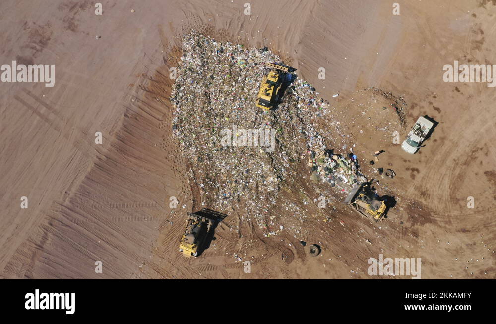 Trash trucks leveling waste polluting products. Aerial top down view of ...