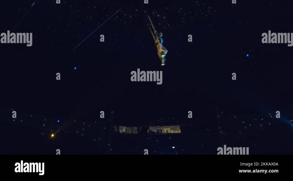 Circus show, young female performer is swinging from the ceiling ...