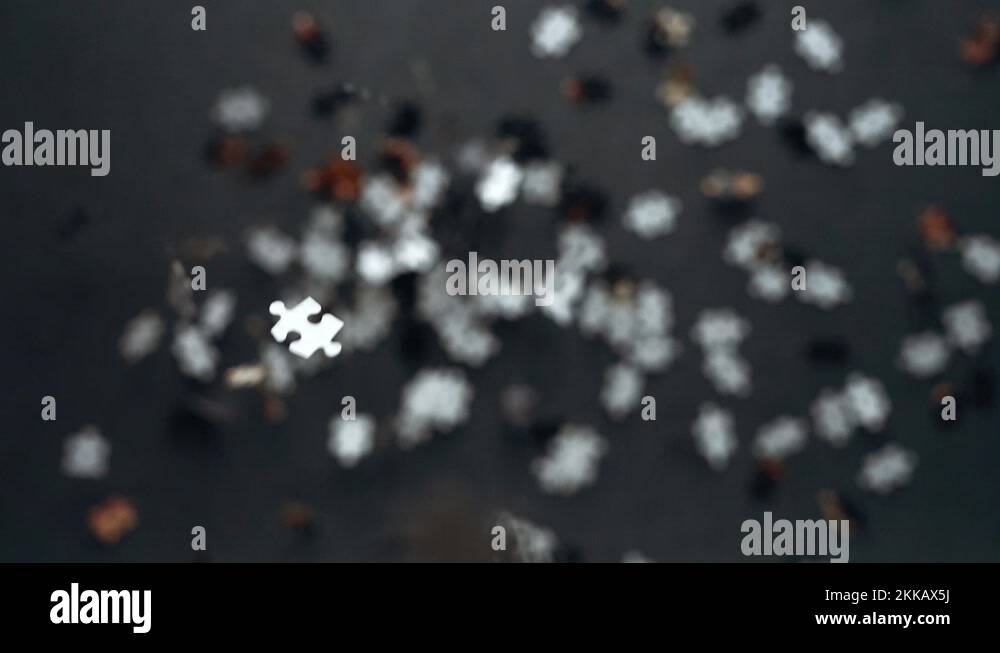 Jigsaw puzzle pieces falling down in slow motion onto gray table with ...