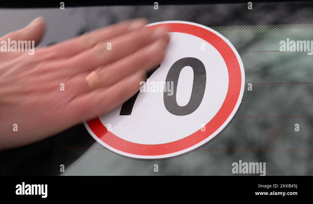 Round warning sticker with sign 70 of speed limit attached to glass of ...
