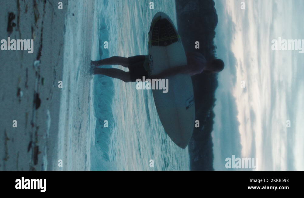 Back view of surfer holding surfboard on beach in Bali. Gimbal ...