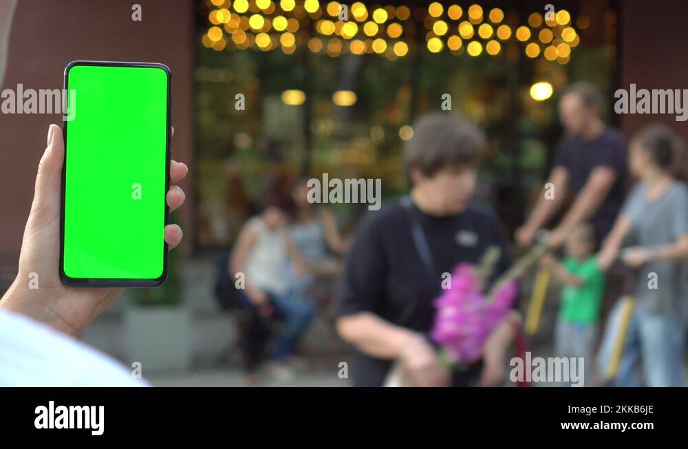 Close up hands woman holding phone with vertical green screen on busy street Stock Video Footage ...