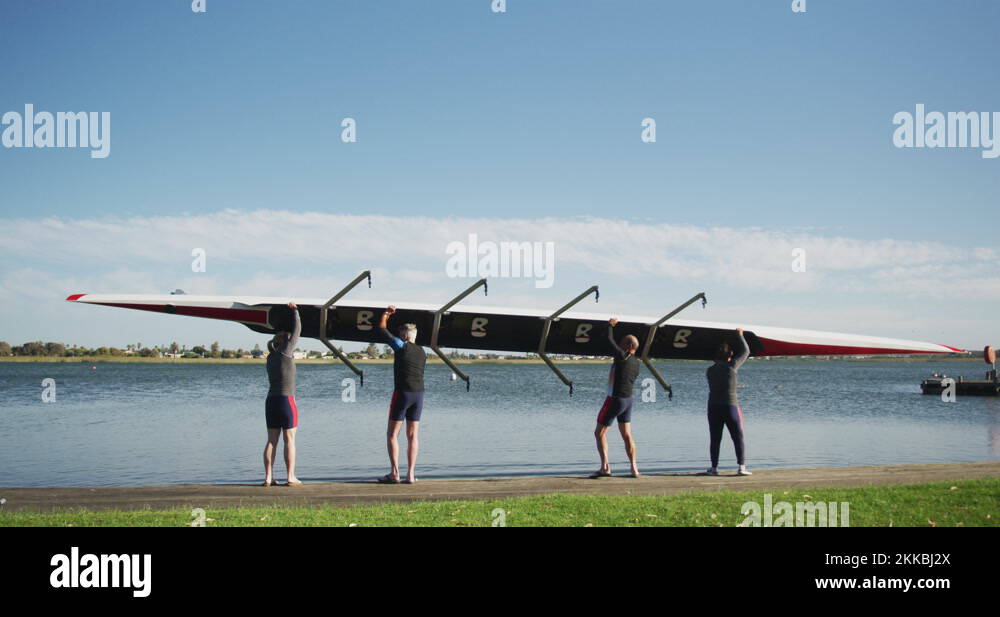 Four senior caucasian men and women carrying a rowing boat together ...