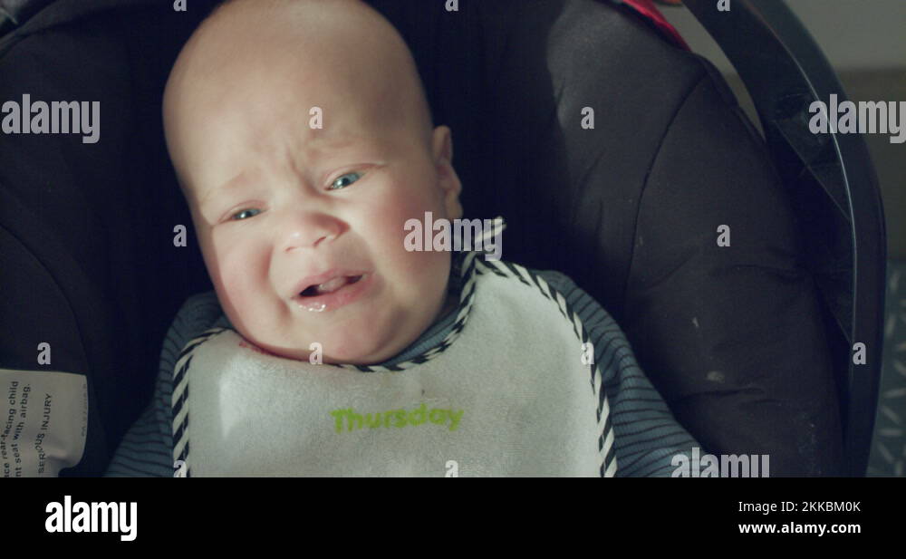 Perplexed baby boy with blye eyes lying, crying and looking into camera ...