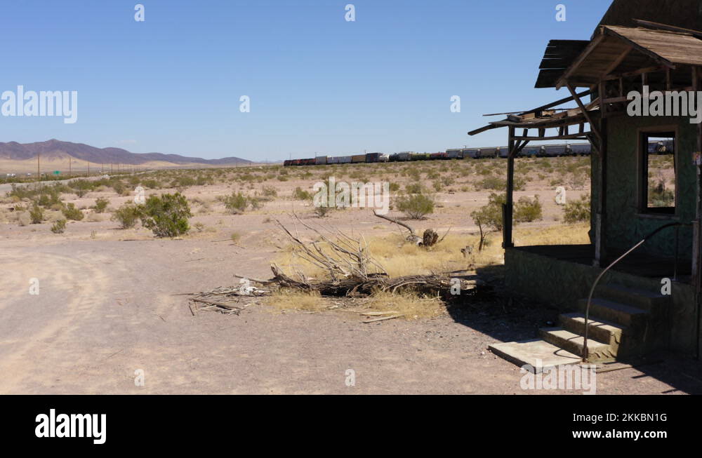 Run down abandoned home sits alone while cargo freight train passes ...