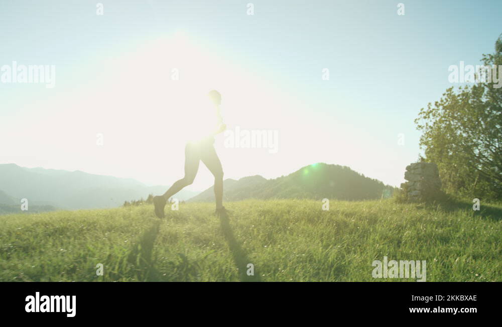 Athlete woman running on top of a hill in sunset and reach the goal ...