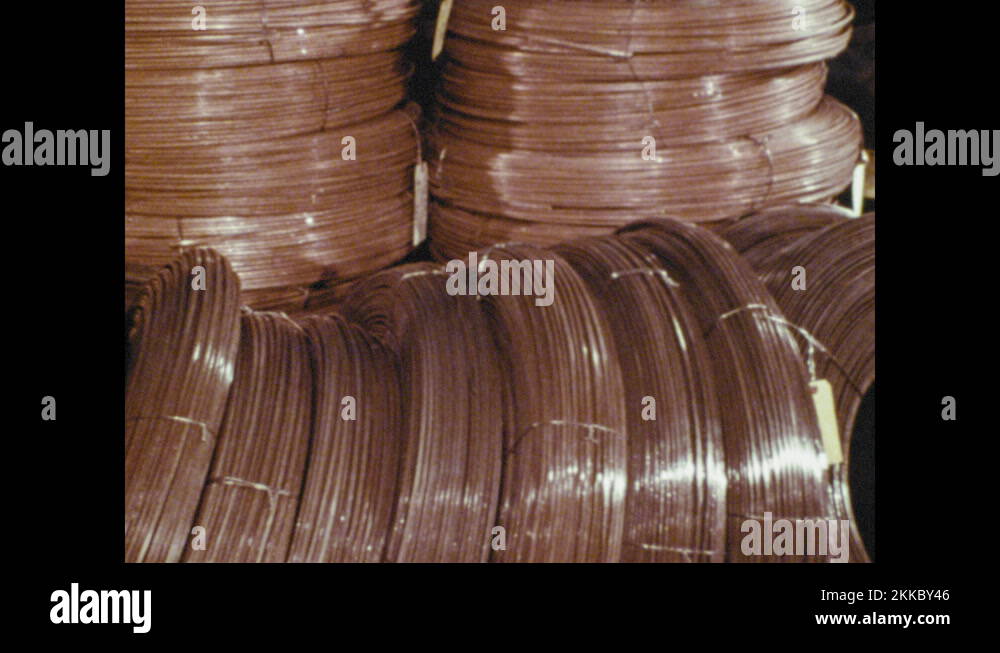 1970s: Coils of metal wire. Man in white lab coat sits at microscope ...