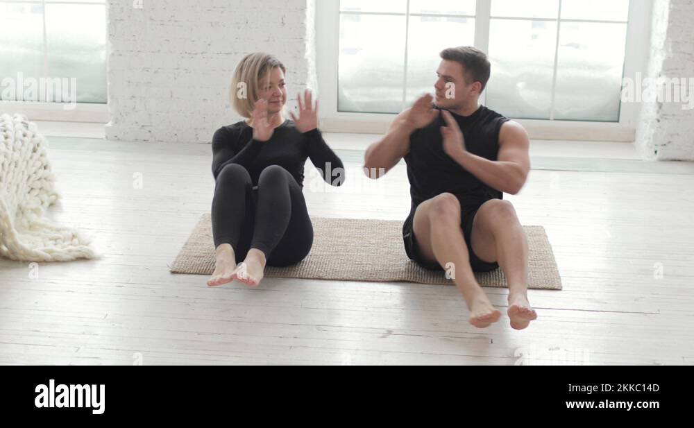 Man and woman doing abs crunch exercise and giving each other high five ...