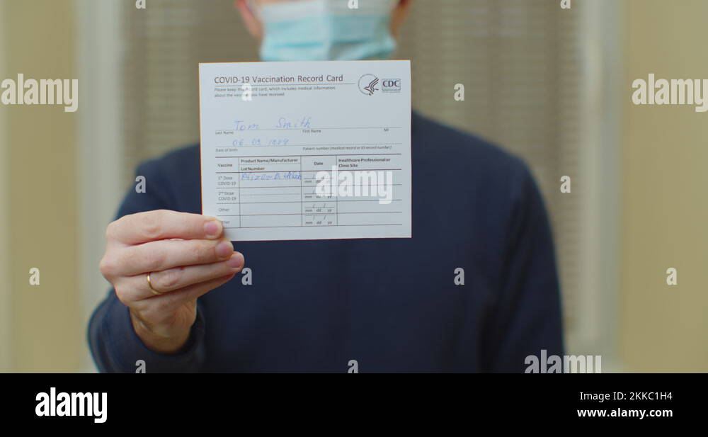 Man in madical mask is holding a vaccination record card. Passport of ...