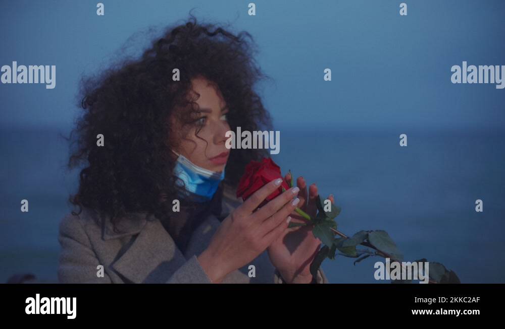 Close-up girl takes off the medical mask and sniffs the rose. She doesn ...