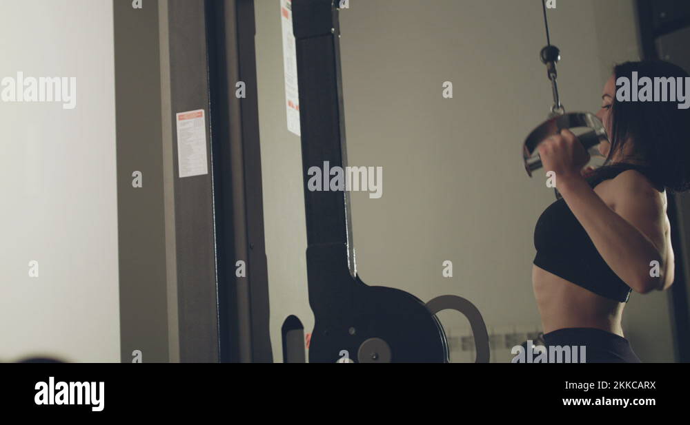 Female athlete works out with the simulator to pump chest muscles in a ...