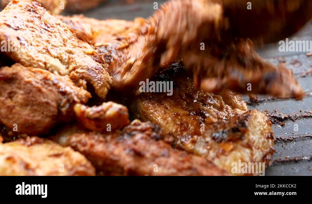 Hand holds a tongs roasting chicken marinated with chinese hot spicy ...