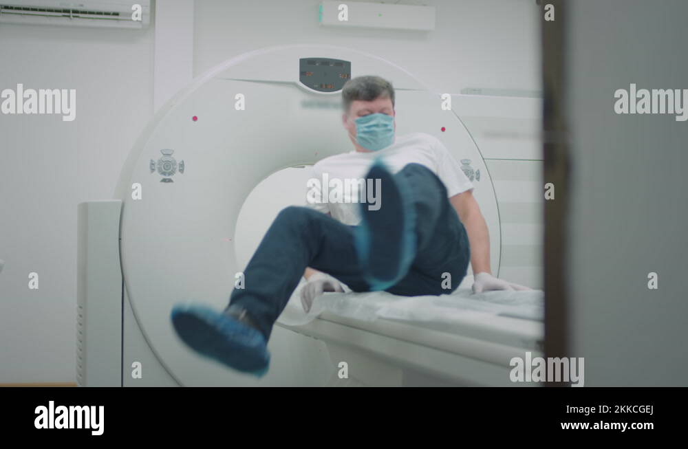 Doctor makes an MRI scan for a patient in a clinic. The male lies in ...