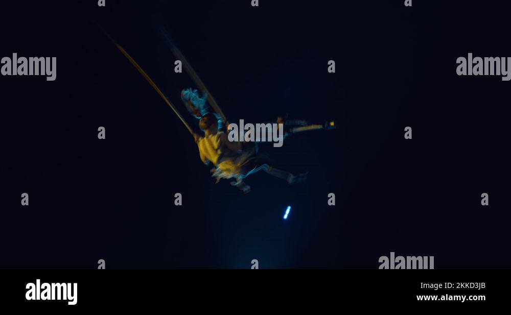 Circus acrobat is performing on stage of a circus, swinging on a ...