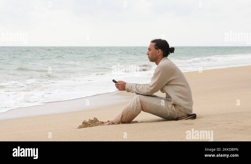 Freelancer finish remote work, shut down laptop. Man sit on sand at sea ...
