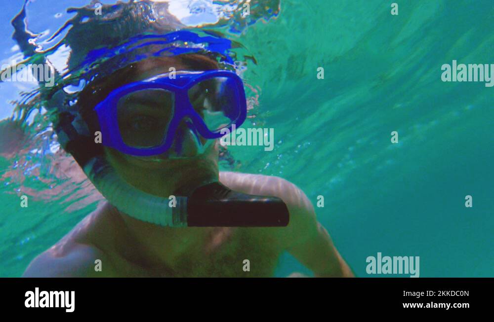 Snorkeling in Hawaii. Young man submerges his face underwater with the ...