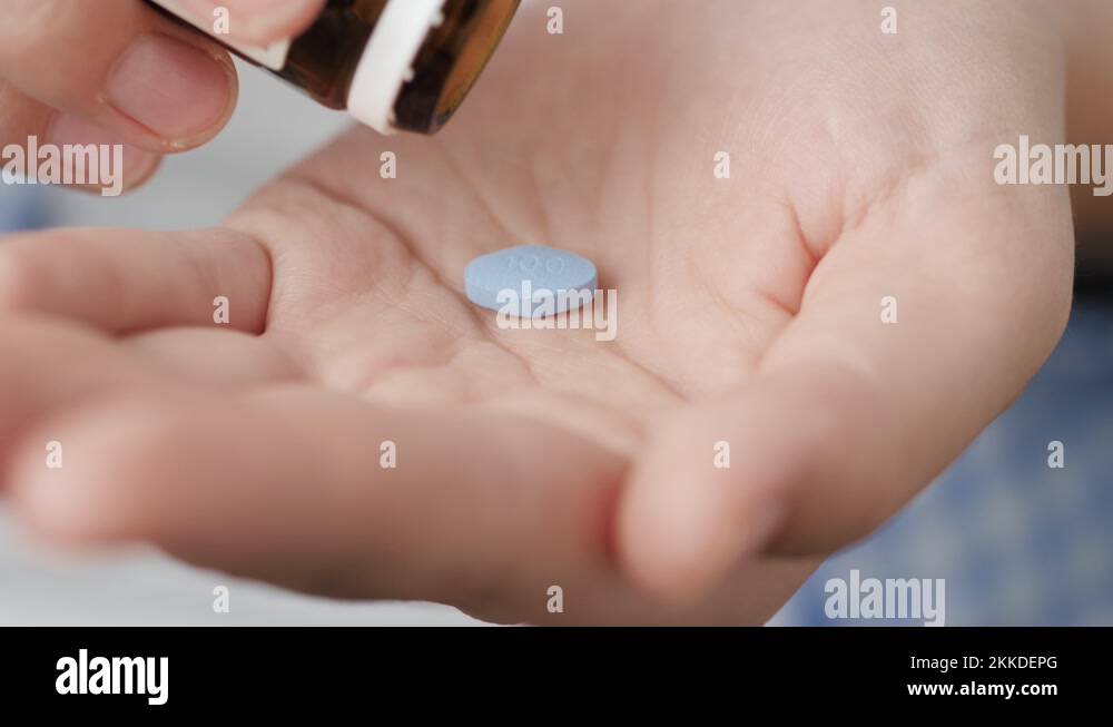 Two big blue diamond-shaped pills labeled 100 fall into palm of hand ...