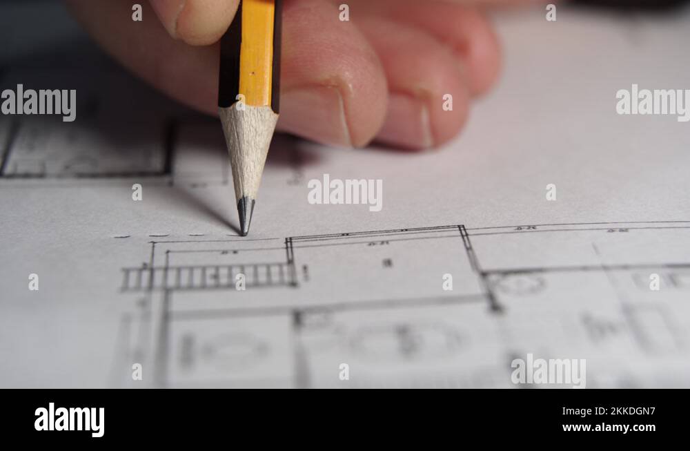 Engineer drawing with pencil on white paper, adding lines on house plan ...