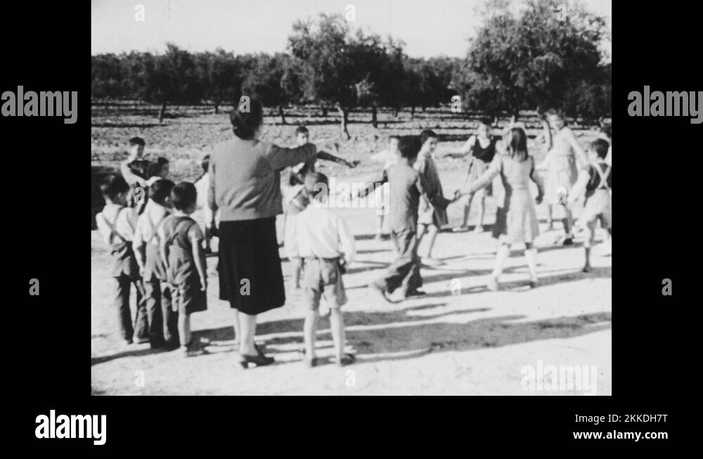 1960s: Kids play outside. Man and boy walk with mule down country lane ...