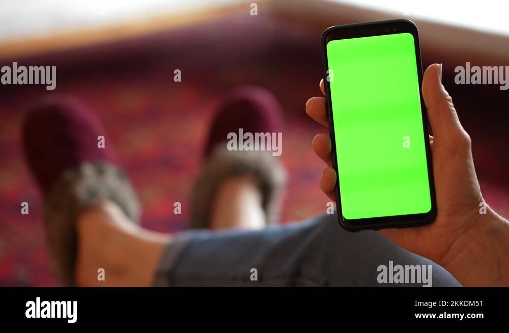 Closeup of woman holding phone with green screen chroma key with feet ...