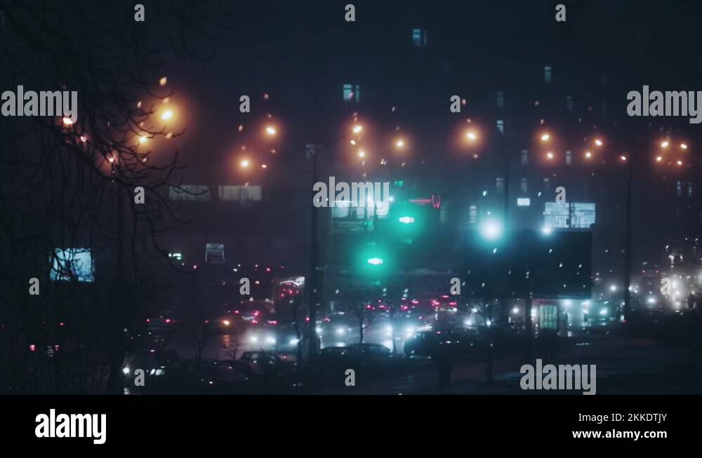 Night city street view with traffic on foggy winter, trees and car ...