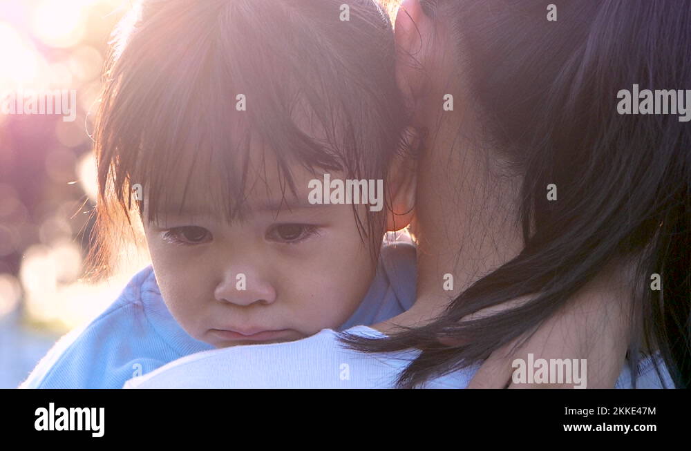 Mother comforting her crying little girl in an outdoor park. parenthood ...