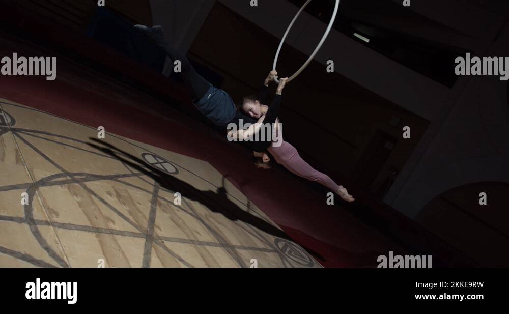 Balance and athleticism of two aerial gymnasts hanging on a hoop ...