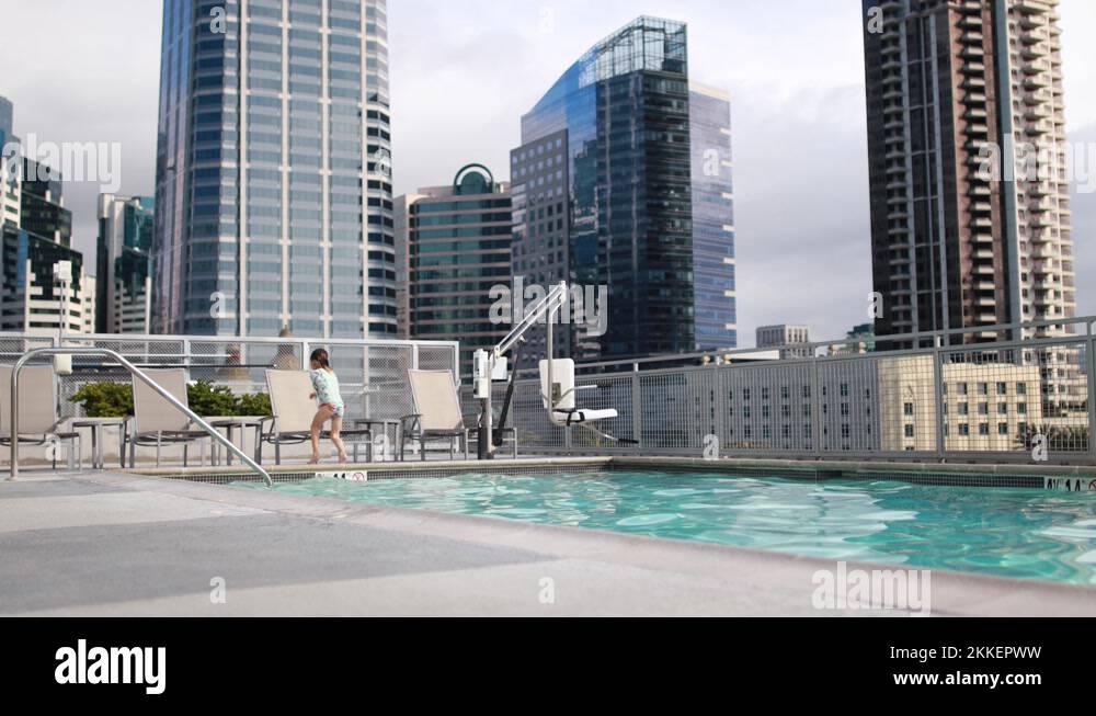 A young girl enjoys jumping in and out of a pool at a rooftop luxury ...