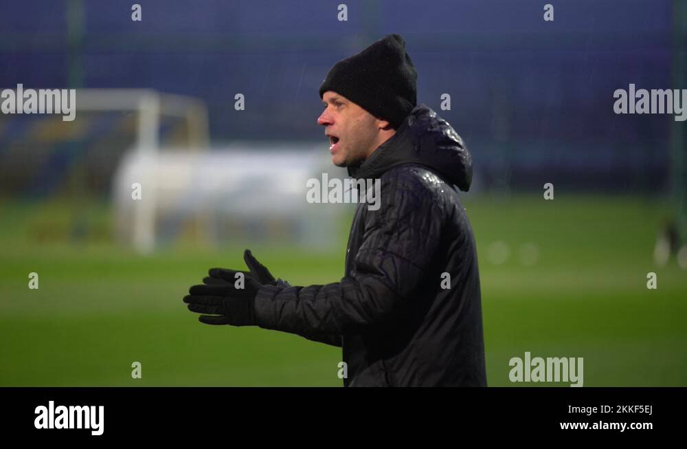 Football team coach in rain cheering team and clapping hands ...