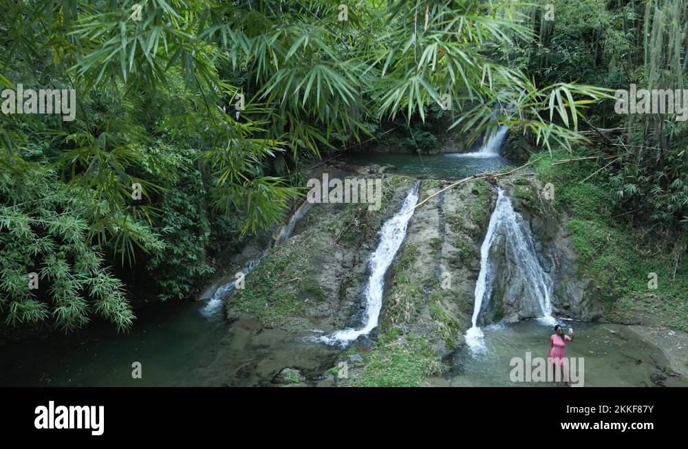 Ascending aerial view of a young lady taking a selfie at the base of a ...