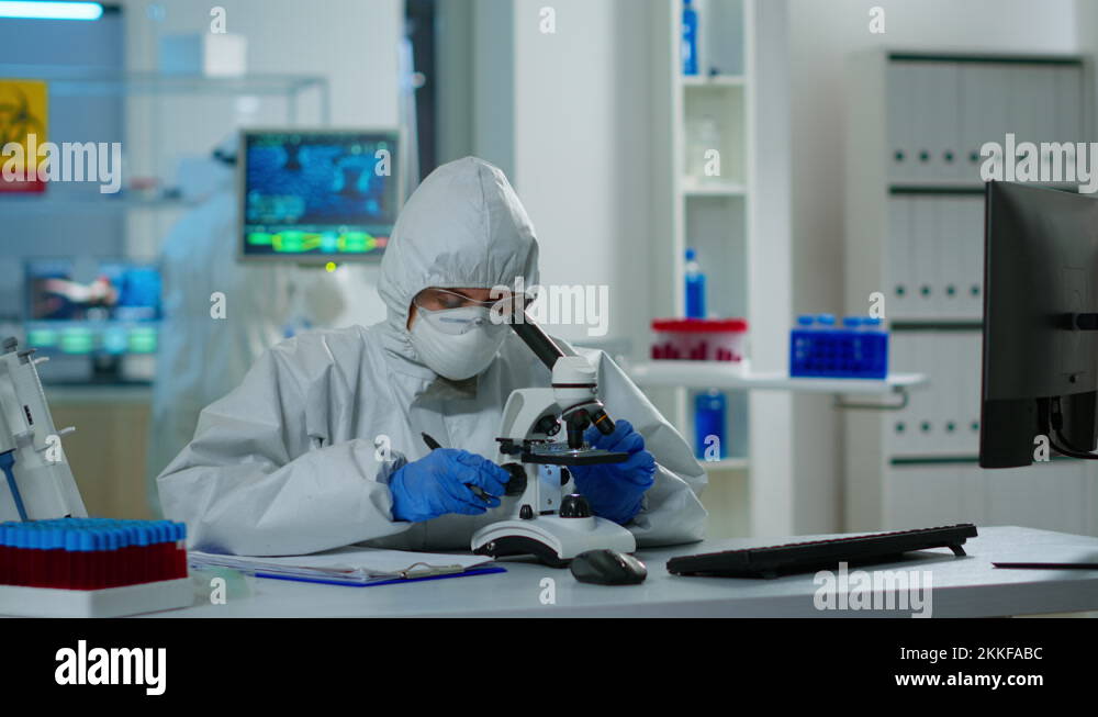 Medical research scientist in ppe suit conducting DNA experiments under ...