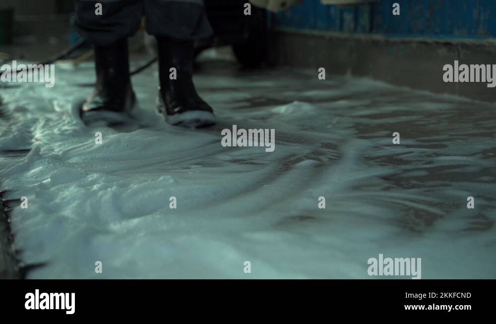 A Caucasian man works in a car wash. The feet in the boots of a car ...