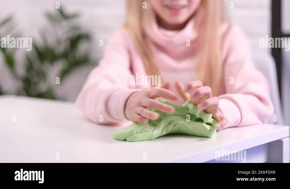 Girl stretching green slime to the sides. kids hands playing slime toy ...