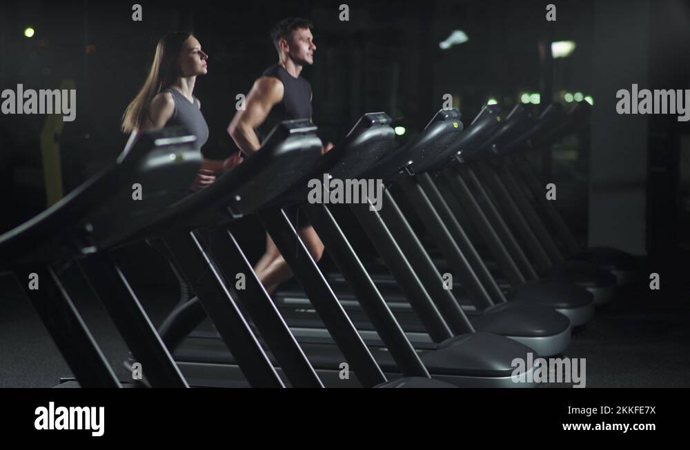 Wellness, female and man athlete run on a treadmill, two runners ...