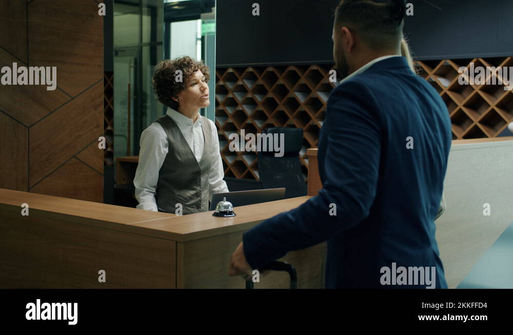 Hotel receptionist talking to guests giving key cards welcoming ...