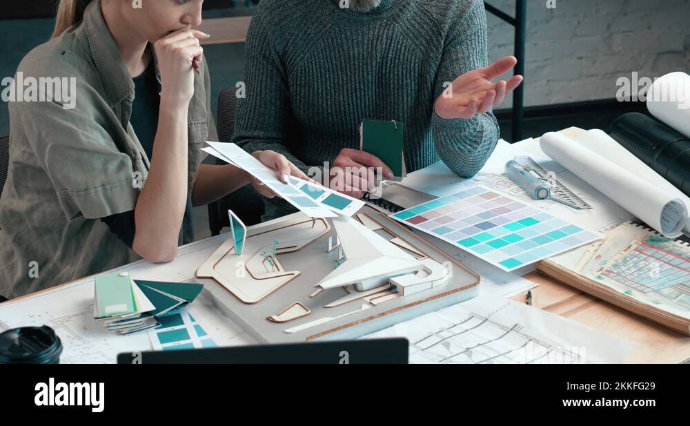 Woman and Man Design Experts with Model of Building talking in Office ...
