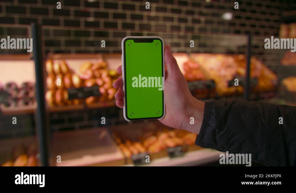 Hand man uses holding a mobile telephone with a vertical green screen ...