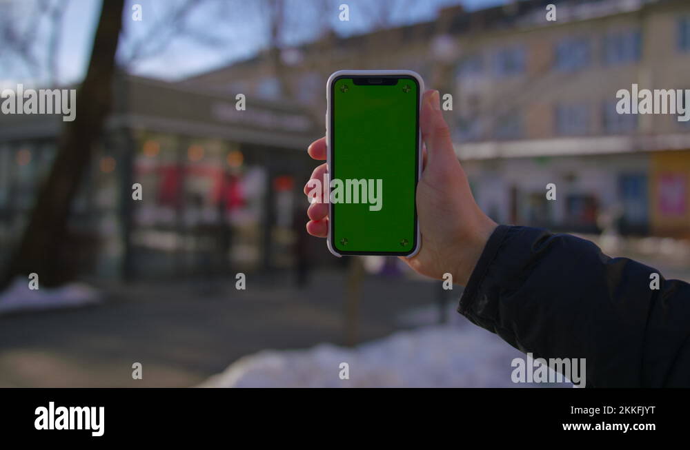 Hand man uses holding a mobile telephone with a vertical green screen ...