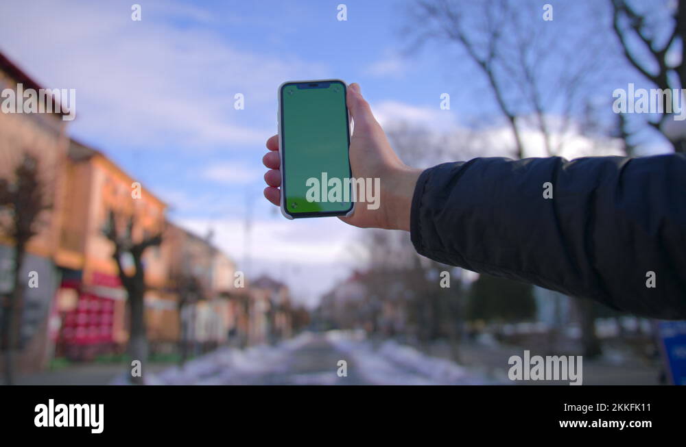 Hand man uses holding a mobile telephone with a vertical green screen ...