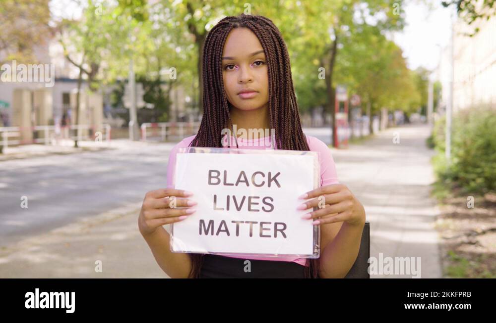 A young black woman shows a Black Lives Matter sign to the camera in ...