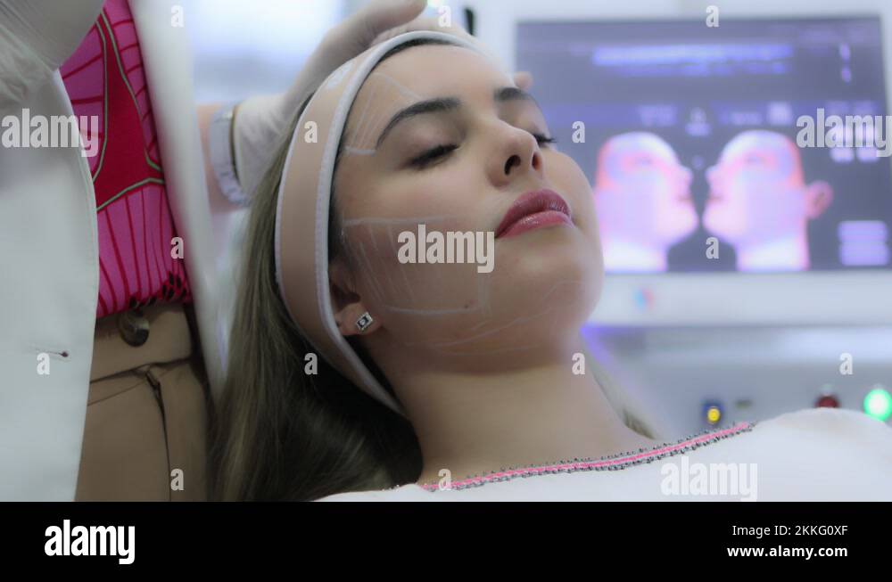 Beautician makes marks on a young woman's face, marking areas for a ...