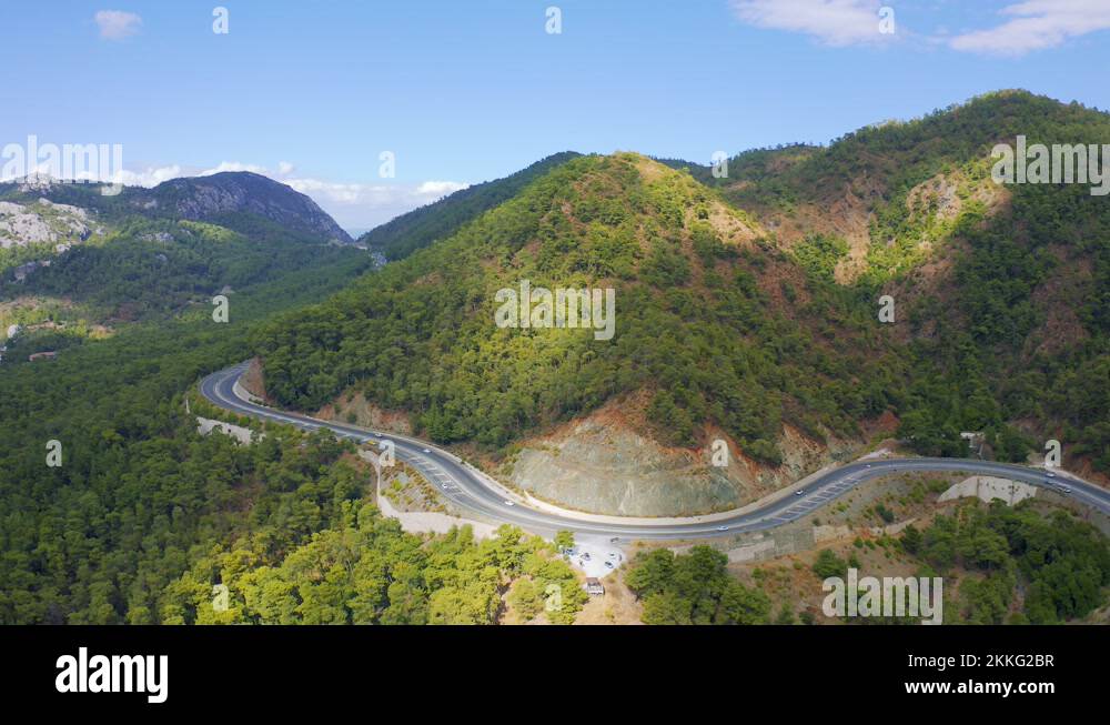 Cars drive along a scenic highway in a mountainous area. Aerial top ...