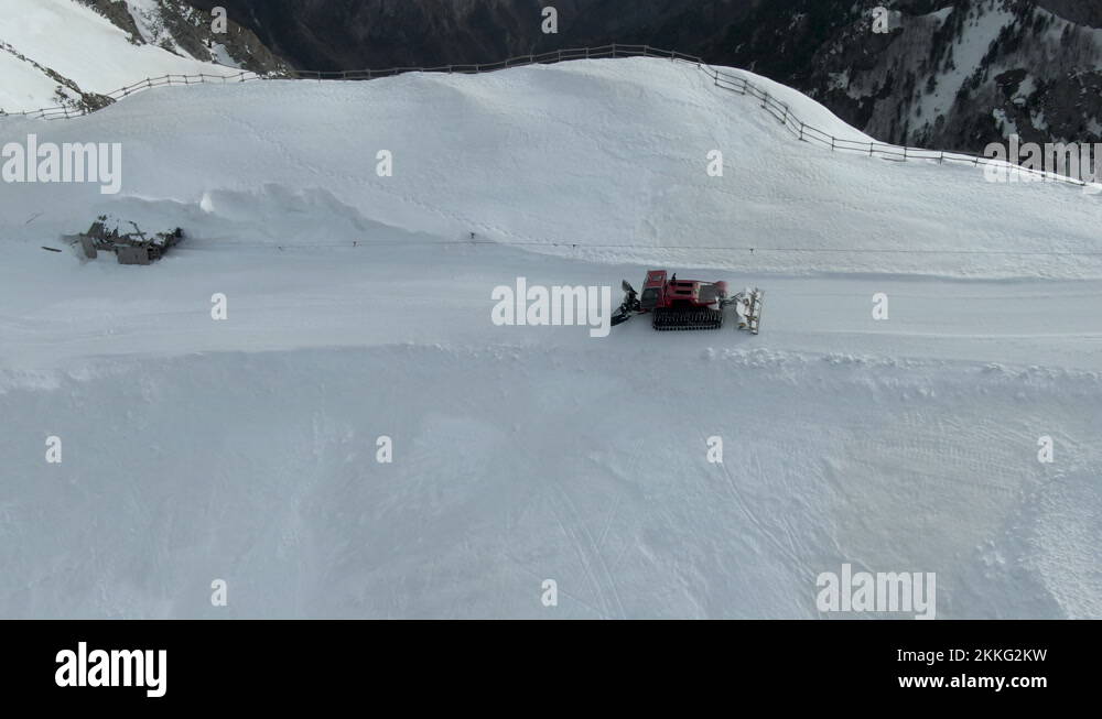 Snow groomer driving down snowy road a top mountain cliff. Amazing top ...