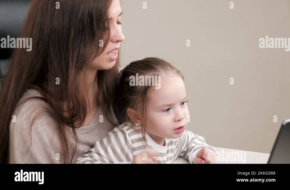 Mom and baby work on the computer as a freelancer at home remotely ...