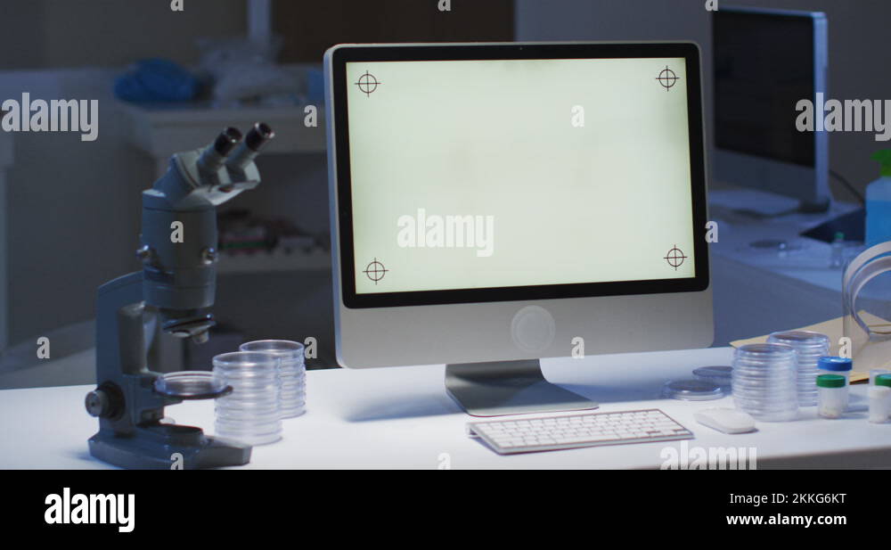Desktop computer with illuminated screen at a workstation in an empty ...