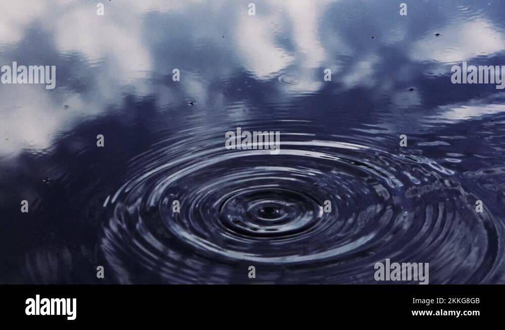 Water drops falling into perfect lake reflection creating beautiful ...