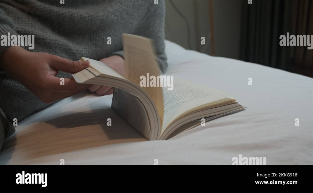 Flipping Through Pages of a Book Lying Comfortably On Bed. Close up ...